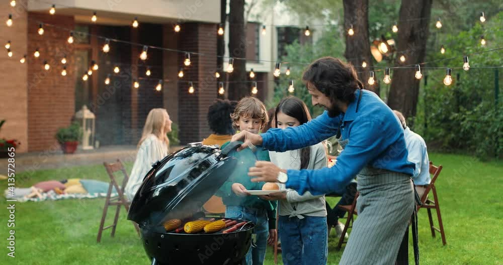 Father cooking food on barbecue for weekend lunch and giving hot meat ...