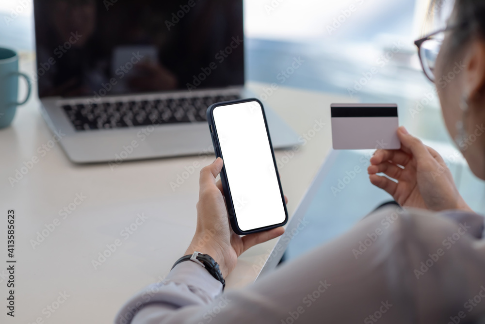 Image of a woman holding a smartphone and credit card in the office ...