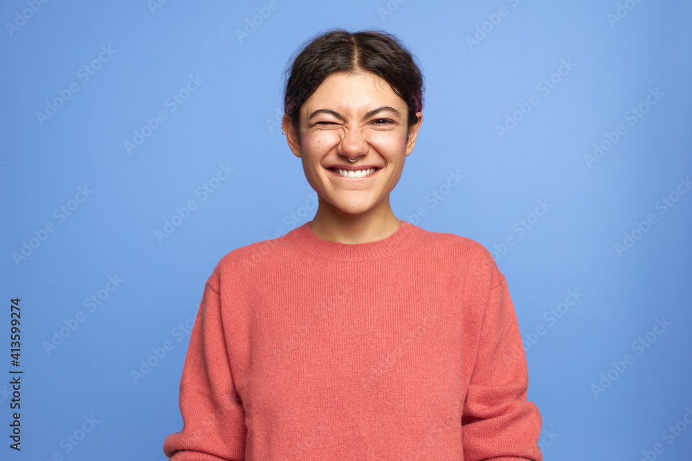 Cute teenage girl in good mood relaxing against blue background with ...