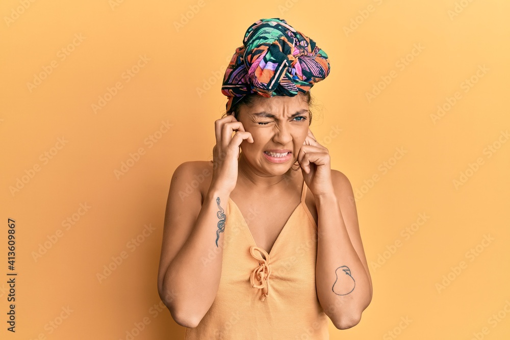 Young hispanic girl wearing hair turban over yellow background covering ...