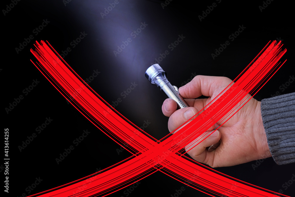 red cross on a metal pocket flashlight in a man's hand on a black ...