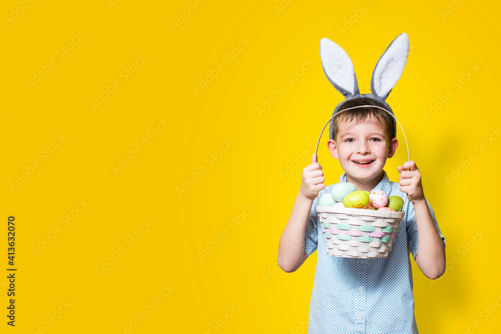 Little cute boy with an Easter basket in his hands and bunny ears on ...