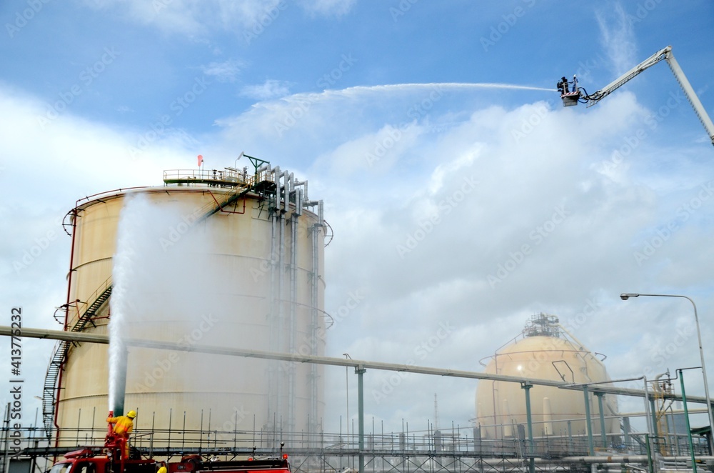 Fireman use fire hose water spray from fire truck to the Large chemical ...