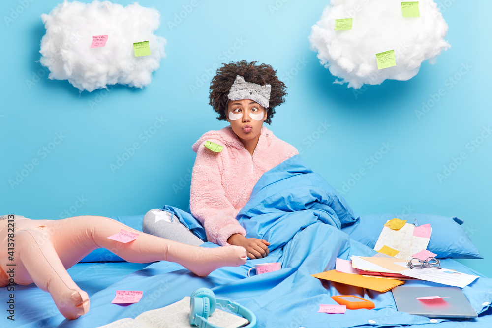 Funny dark skinned curly woman keeps lips rounded makes grimace dressed ...