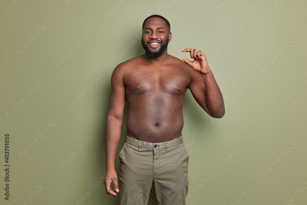 Glad dark skinned man poses with bare torso shapes little gesture tells ...