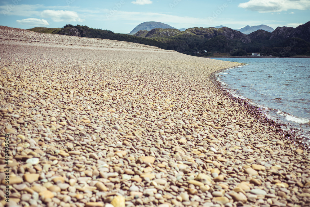 Beautiful pebbled beach on remote island with mountains in scotland ...
