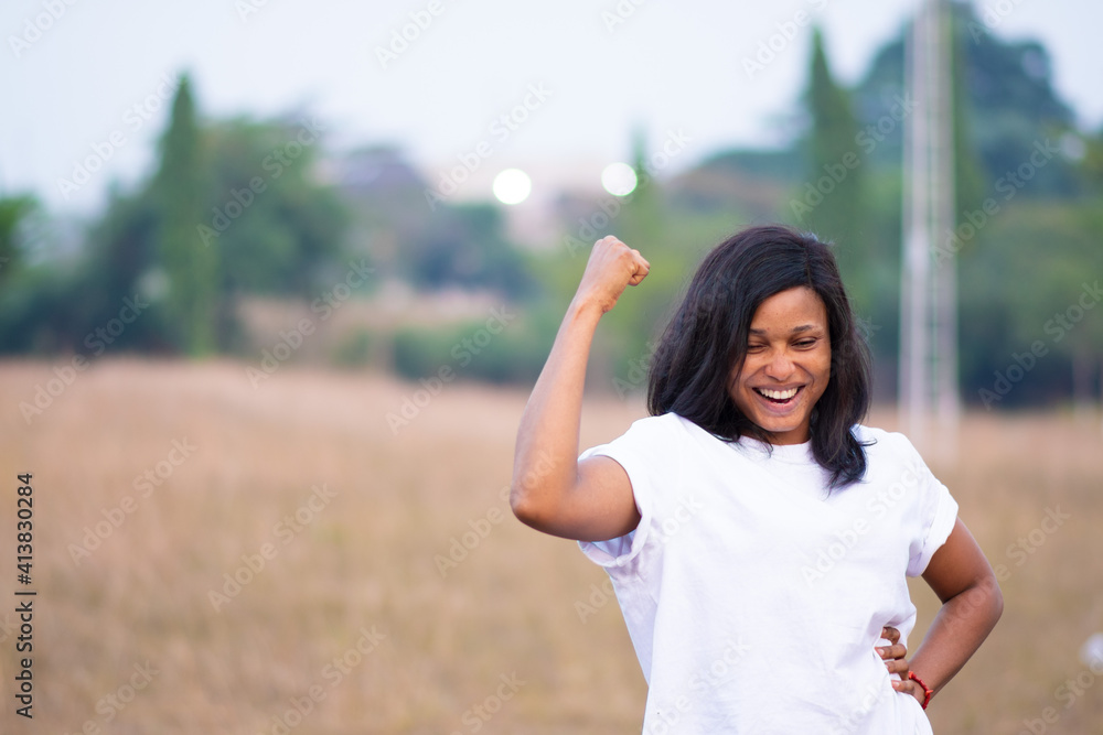 portrait of a young light skin nigerian woman flexing her muscle to ...