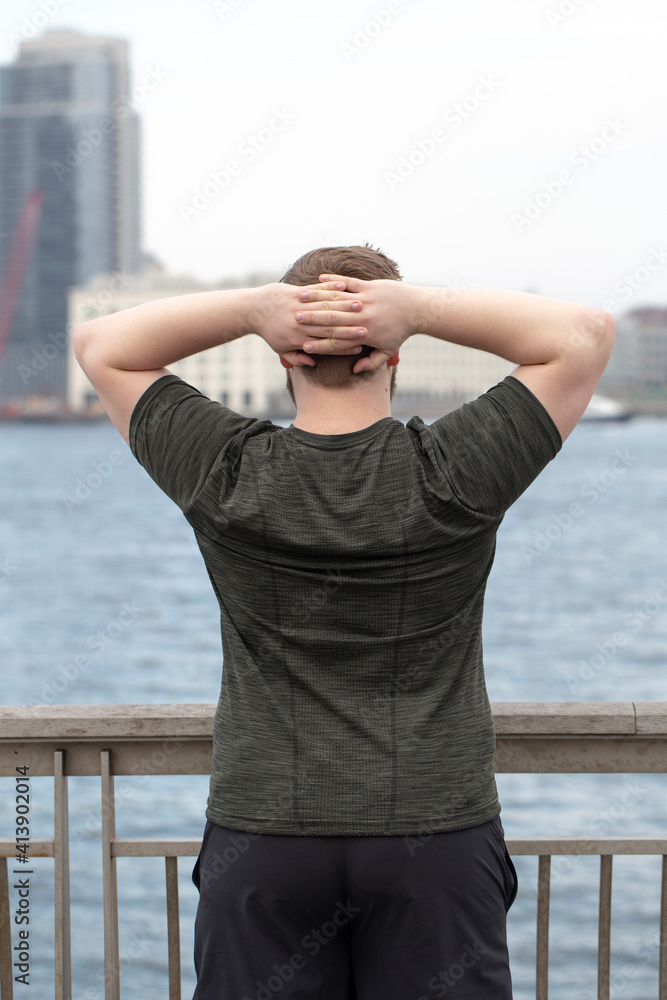 Rear view of overweight man with hands behind head exercising on bridge ...