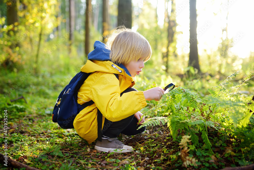 Preschooler boy is exploring nature with magnifying glass. Little child ...