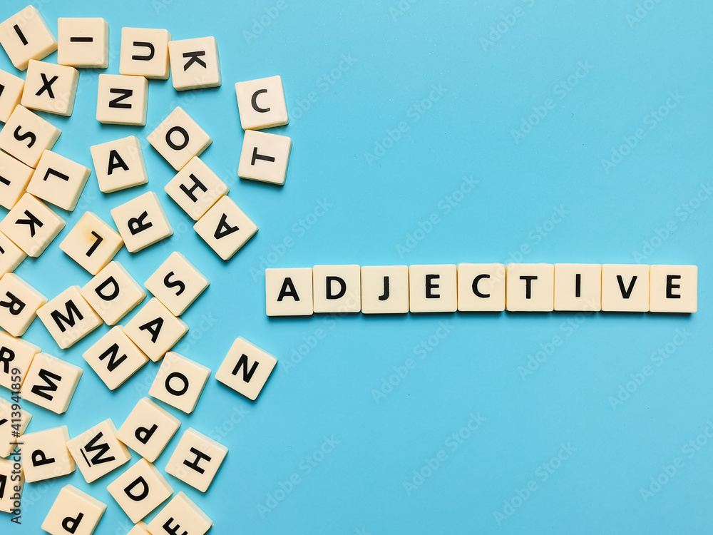 ADJECTIVE word made from square letter tiles on blue background. Stock ...