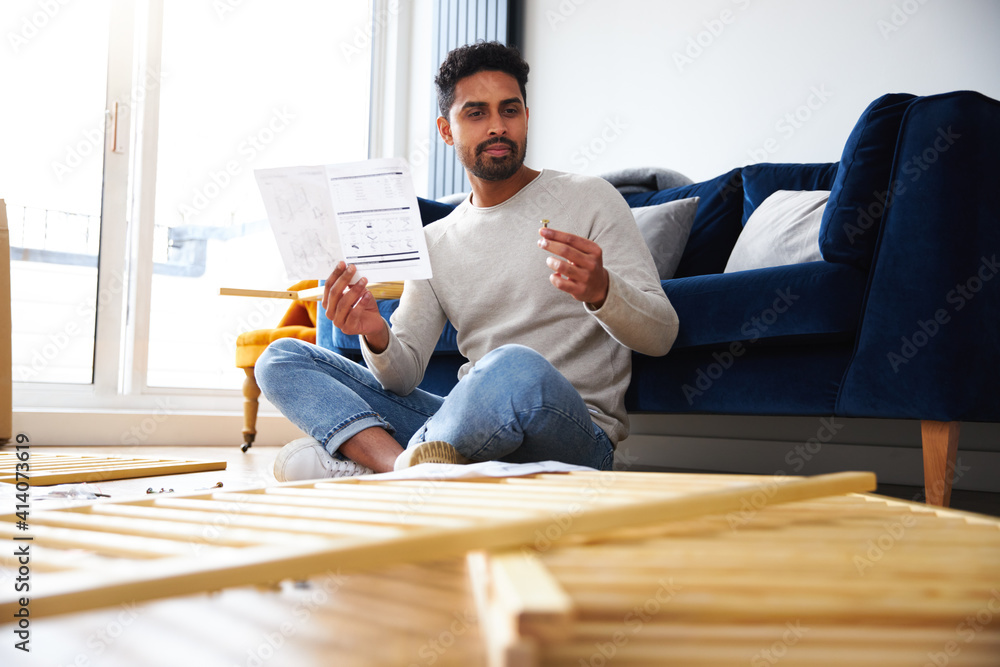 Confused Man In Lounge At Home Reading Instructions For Flat Pack ...