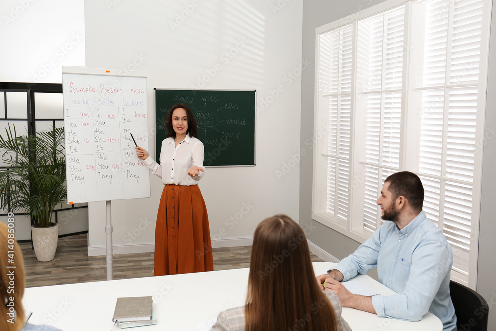 English teacher giving lesson on simple present tense near whiteboard ...