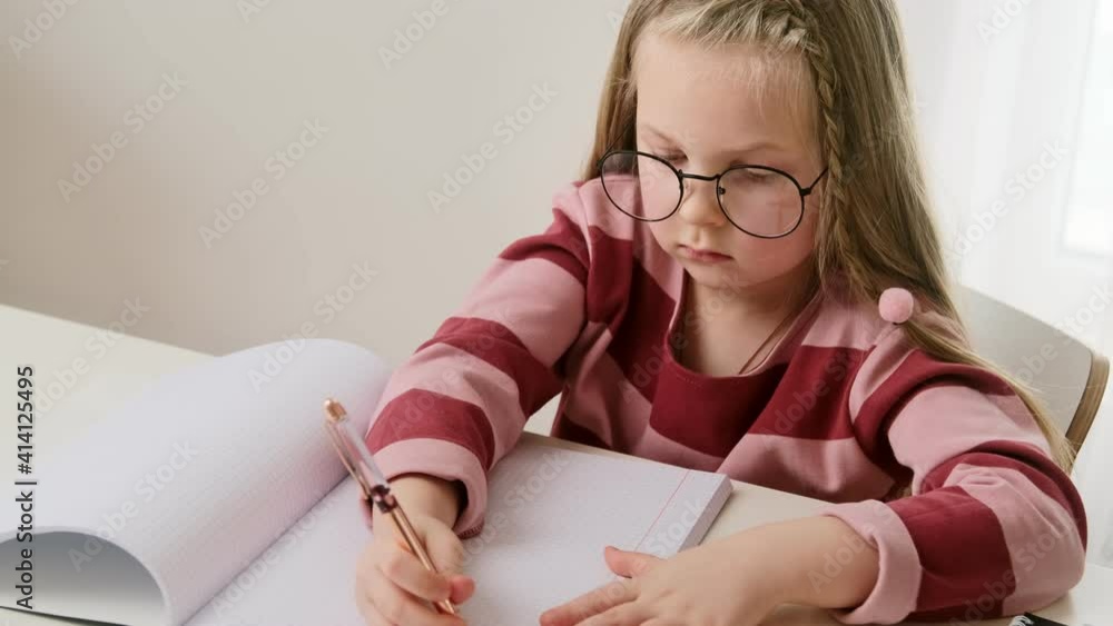 Little smart girl child learning writing a task, doing homework ...