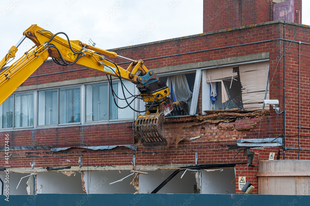 Demolition of an old building with a long reach machine hydraulic jaw ...
