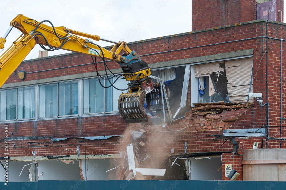 Demolition of an old building with a long reach machine hydraulic jaw ...