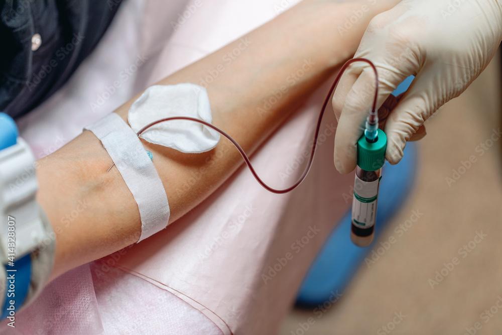 Gentle hands of a nurse taking blood from a patient's vein. Close-up ...