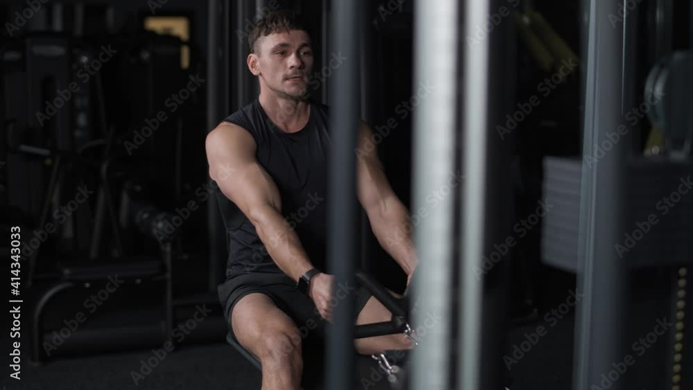 Athletic man in the gym lifting blocks on rowing machine, training on ...