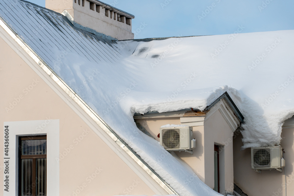 The roofs of the buildings are covered with snow and ice after a big ...