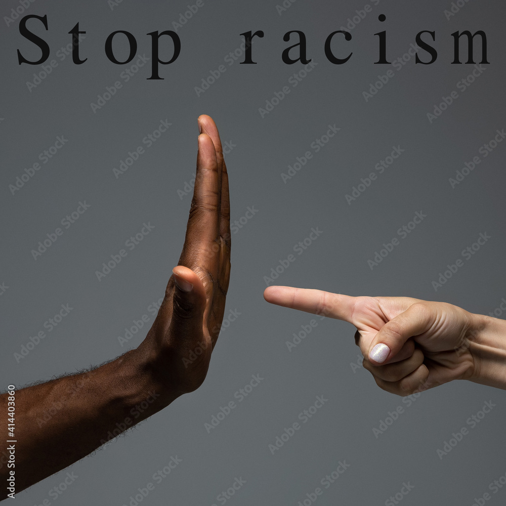 Stop racism. African and caucasian hands gesturing on gray studio ...