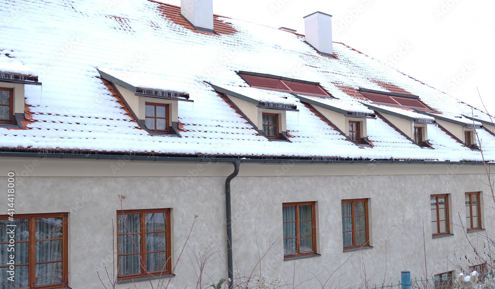 Exterior of apartments with gable roofs and dormers covered with snow ...