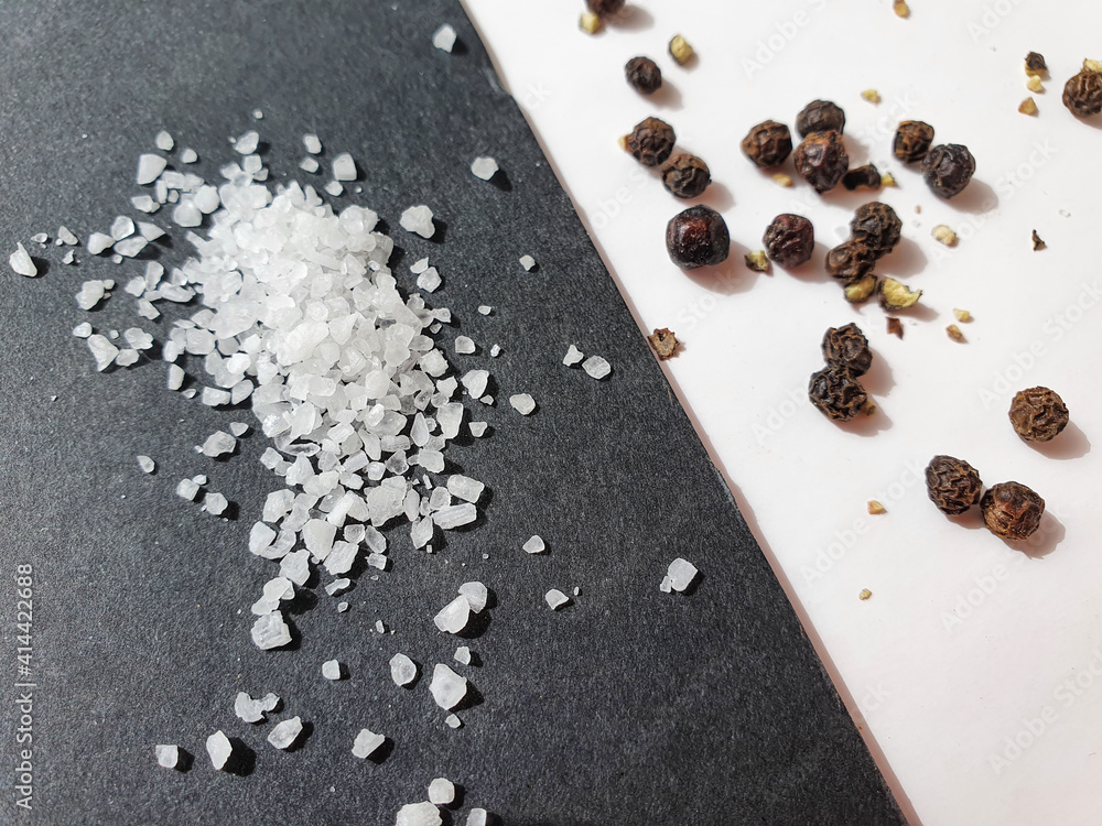 salt and pepper. salt and black pepper. Salt on a black background and ...