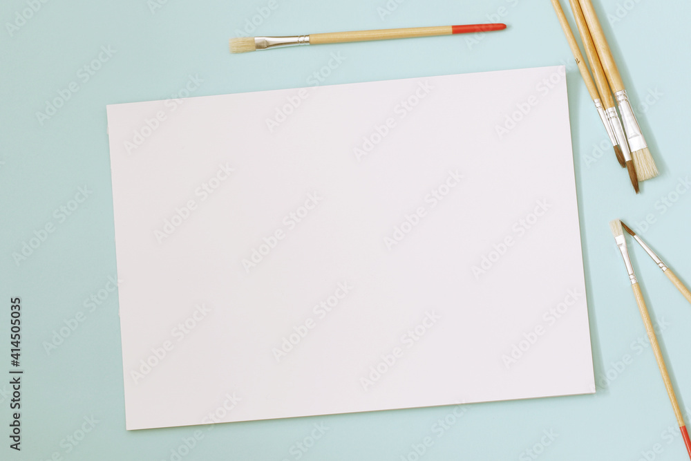 empty blank white paper sheet with paint brushes on the mint green ...