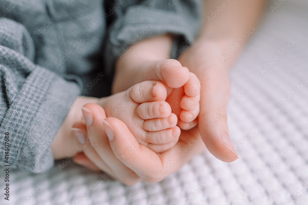 Baby foot in mom`s hands. The feet of a tiny newborn baby on a female ...