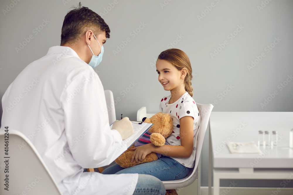 Male doctor talks to the little girl and does a regular medical ...