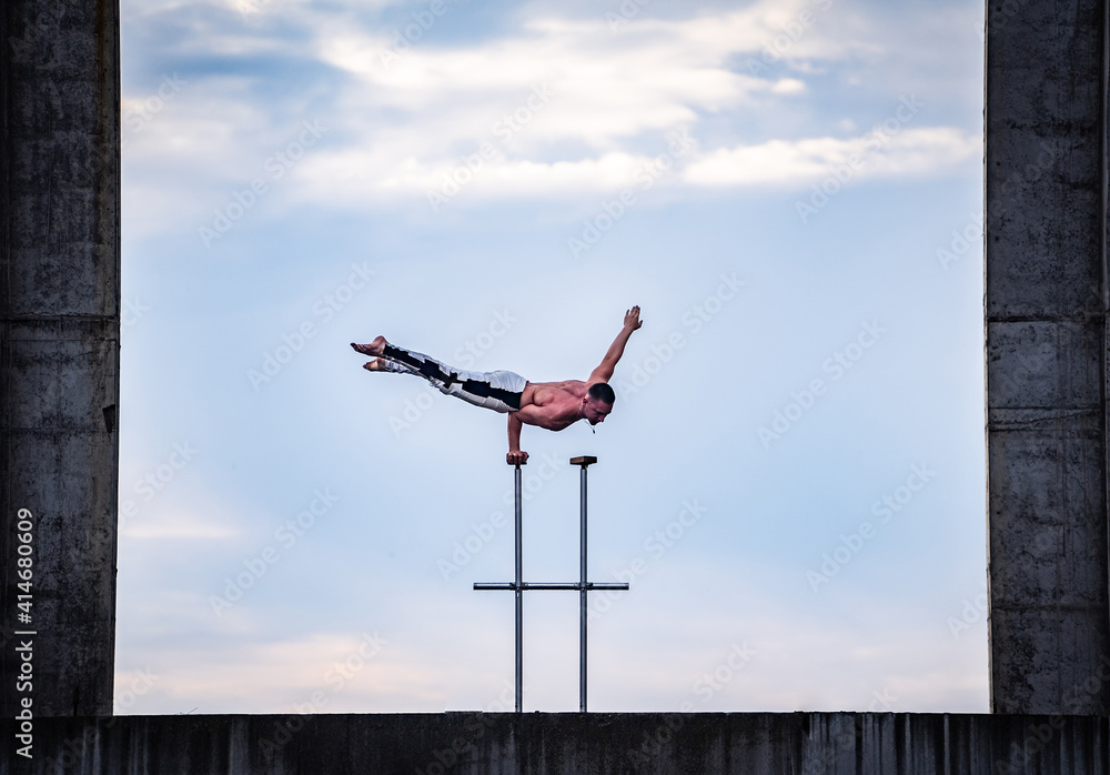 Man keeps balance on one hand on the cloudy sky background. Concept of ...