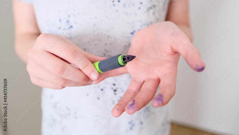boy 8-9 years old holding an ink pen, all fingers are stained with blue ...