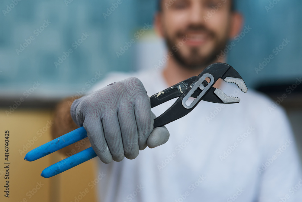 Necessary hand tool. Close up shot of hand of young repairman holding a ...