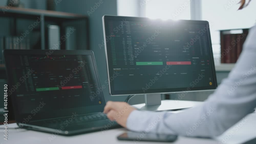 Male broker using modern computers for checking stock market data while ...