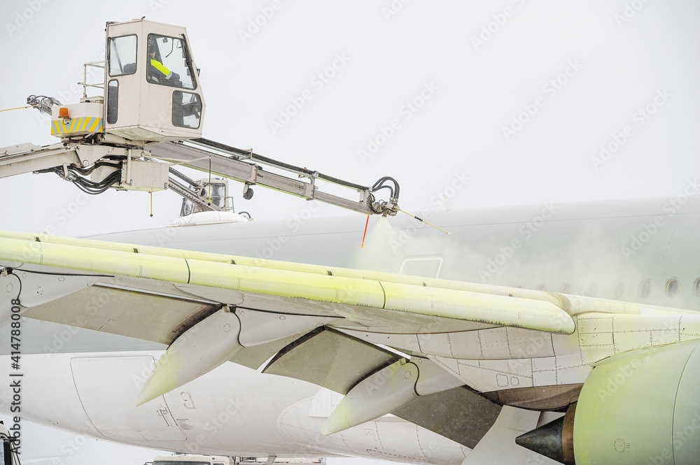 Winter at the airport. Snow storm. Airplane de-icing before take off ...