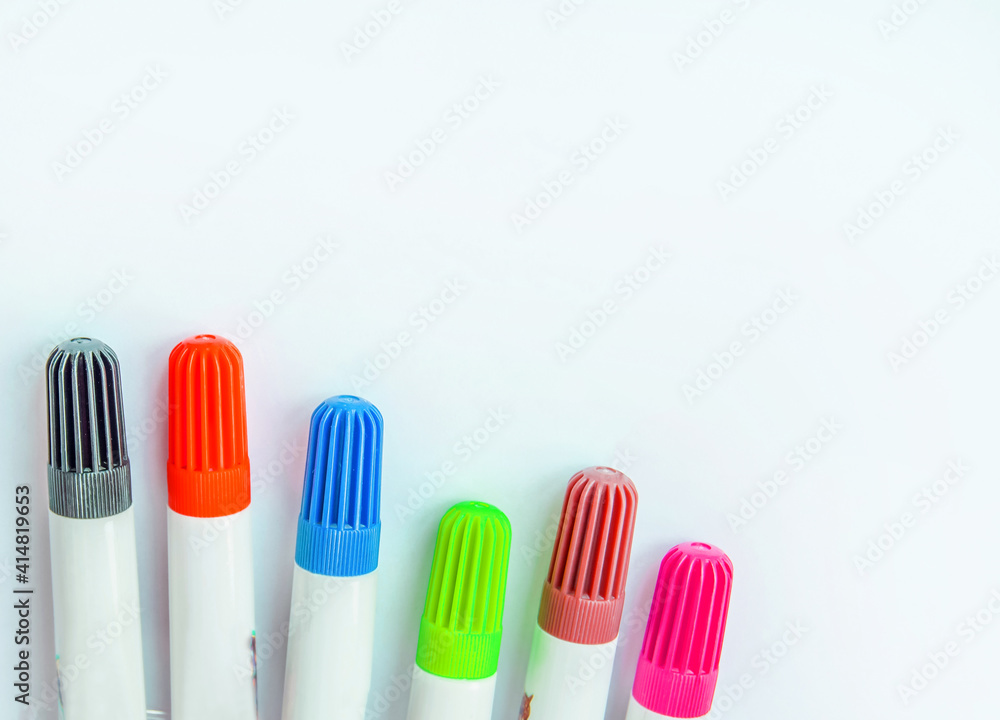 A set of multi-colored markers on the bottom edge on a white background ...