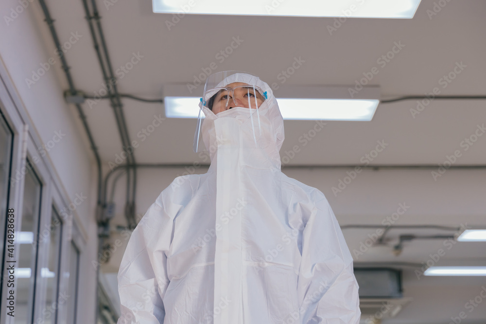 Tired young healthcare worker wearing PPE suit with protective face ...