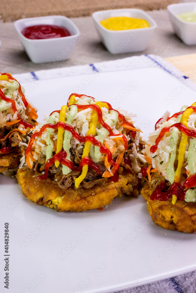 Plato de comida venezolana hecho de tostón con ensalada de col, queso ...
