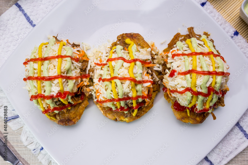 Plato de comida venezolana hecho de tostón con ensalada de col, queso ...