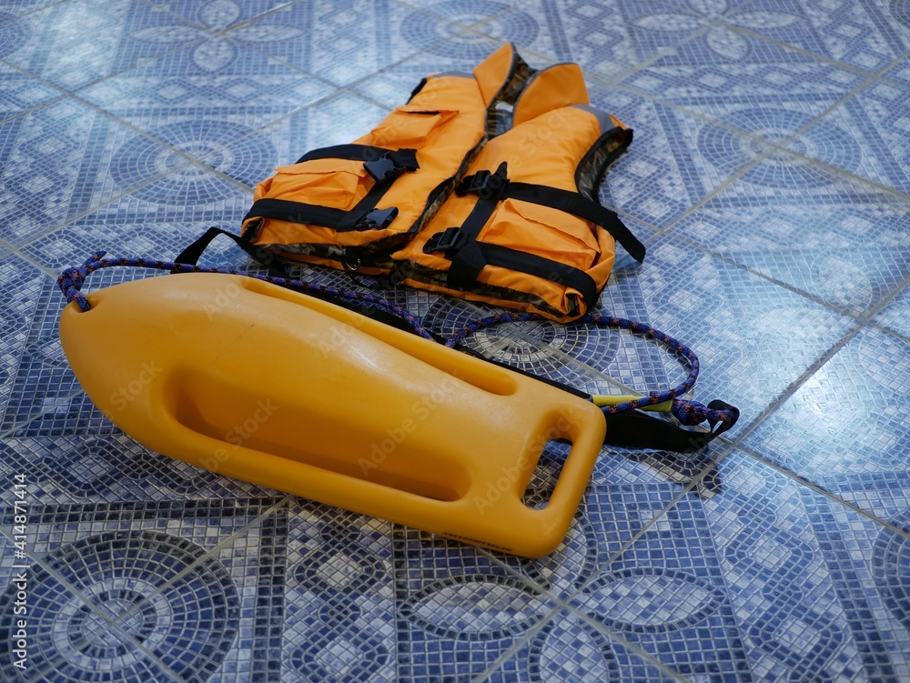 An orange life jacket and an orange plastic rescue torpedo buoy for ...