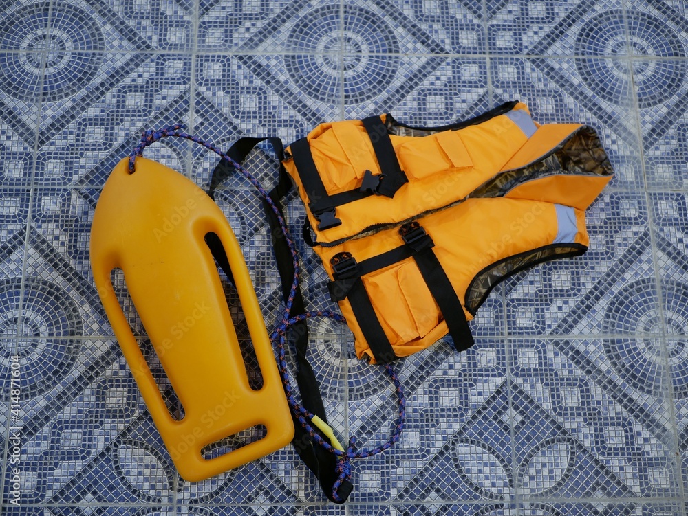 An orange life jacket and an orange plastic rescue torpedo buoy for ...