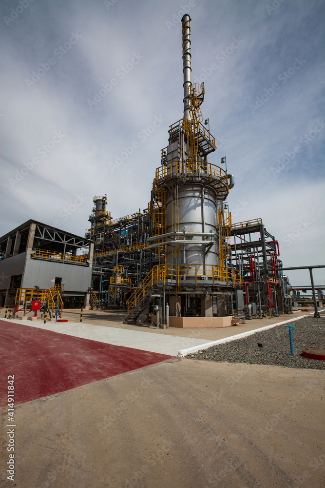 Distillation column and pipelines.Oil refinery plant in desert. On blue ...