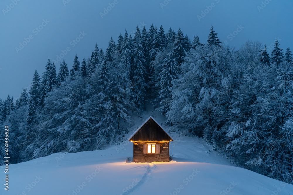 Fantastic winter landscape with glowing wooden cabin in snowy forest ...