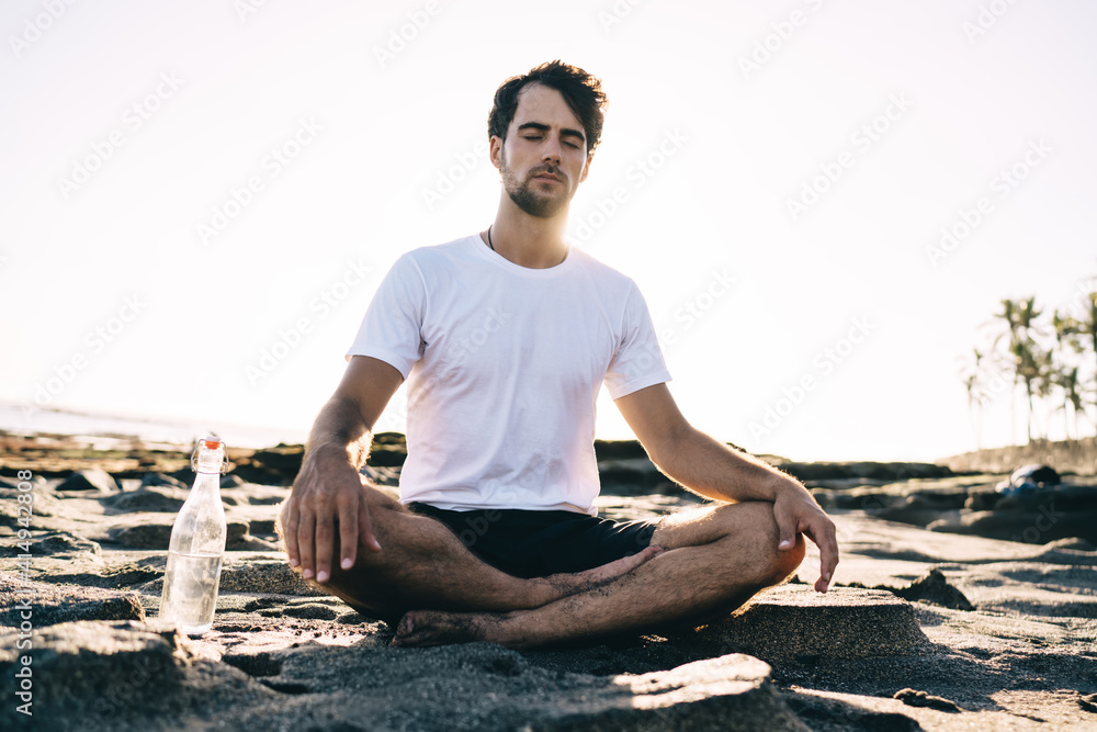 Calm man sitting in lotus pose during meditation Stock Photo | Adobe Stock