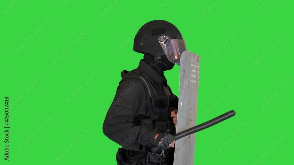 Policeman with full equipment for anti-riot standing covering with a ...
