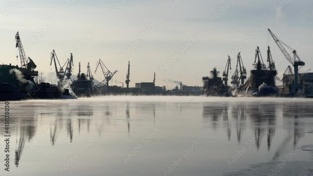 Cranes of of the Baltic shipyard on a frosty winter day, steam over the ...