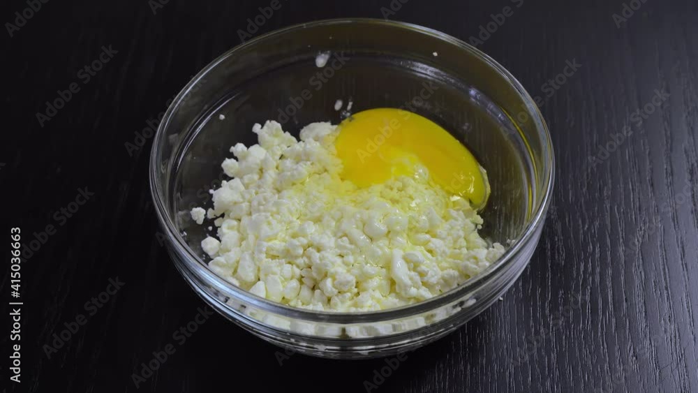 The cook adds a broken egg to a plate of cottage cheese, for further ...