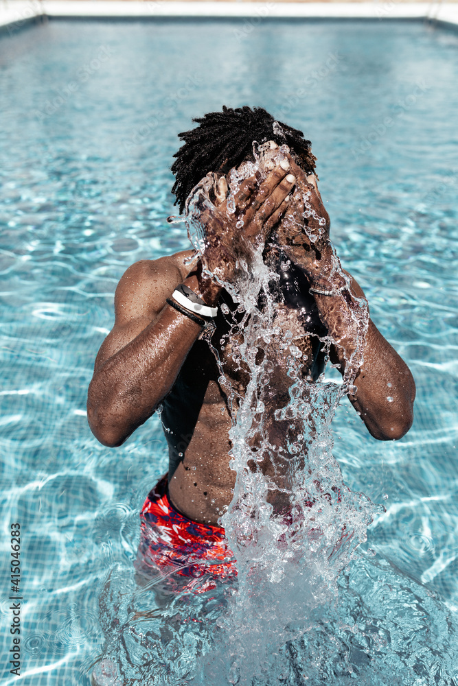 Anonymous African American male in shorts standing in swimming pool and ...
