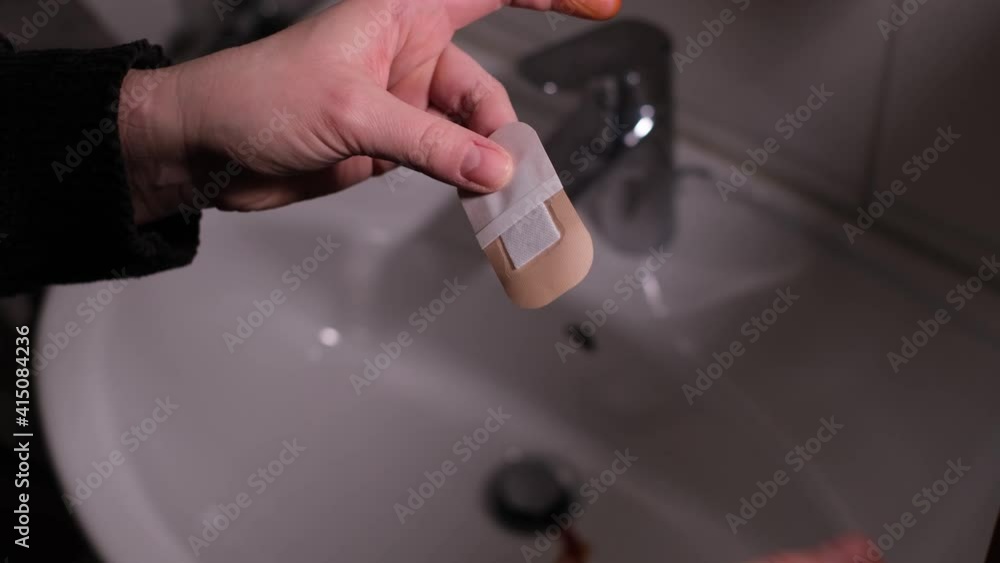 Woman changing a plaster on injured finger. Self first aid at home in ...