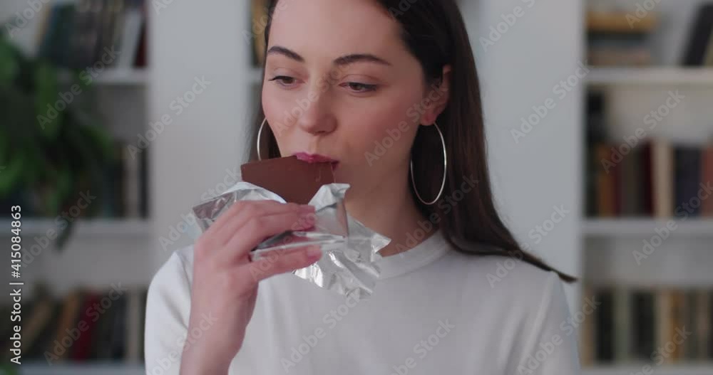 Young Caucasian woman eating chocolate bar close up indoors apartment ...