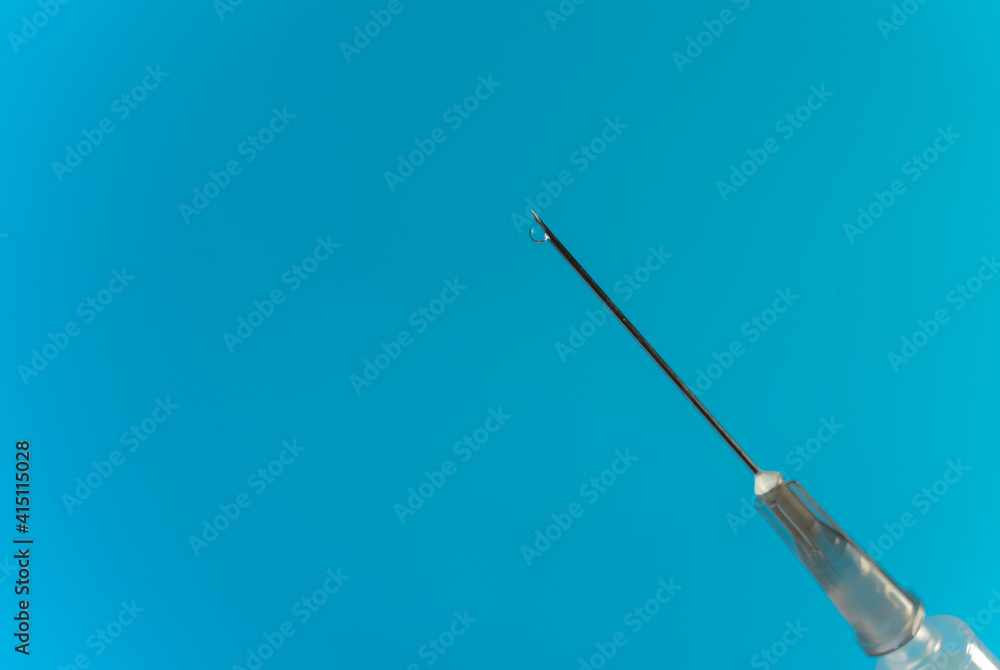 A syringe in the foreground appears from the lower right corner of the ...