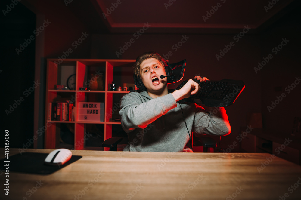 Emotional gamer playing video games on a computer with a keyboard on ...
